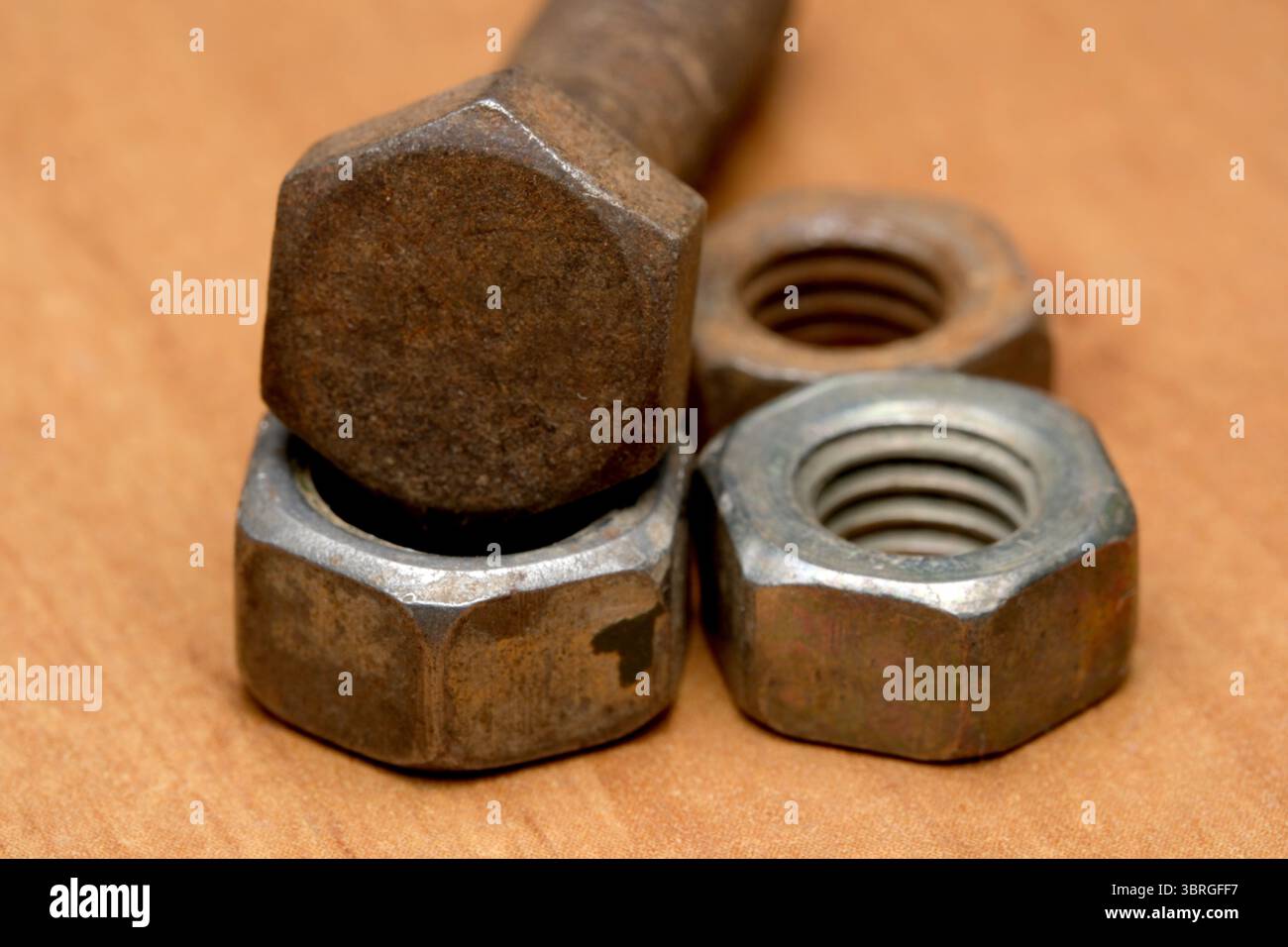 Rusty bolt and nuts lay on a textured wooden surface, showcasing their ...