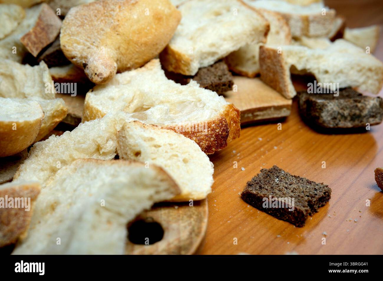 Crusty bread chunks lay strewn across a warm wooden surface, inviting ...