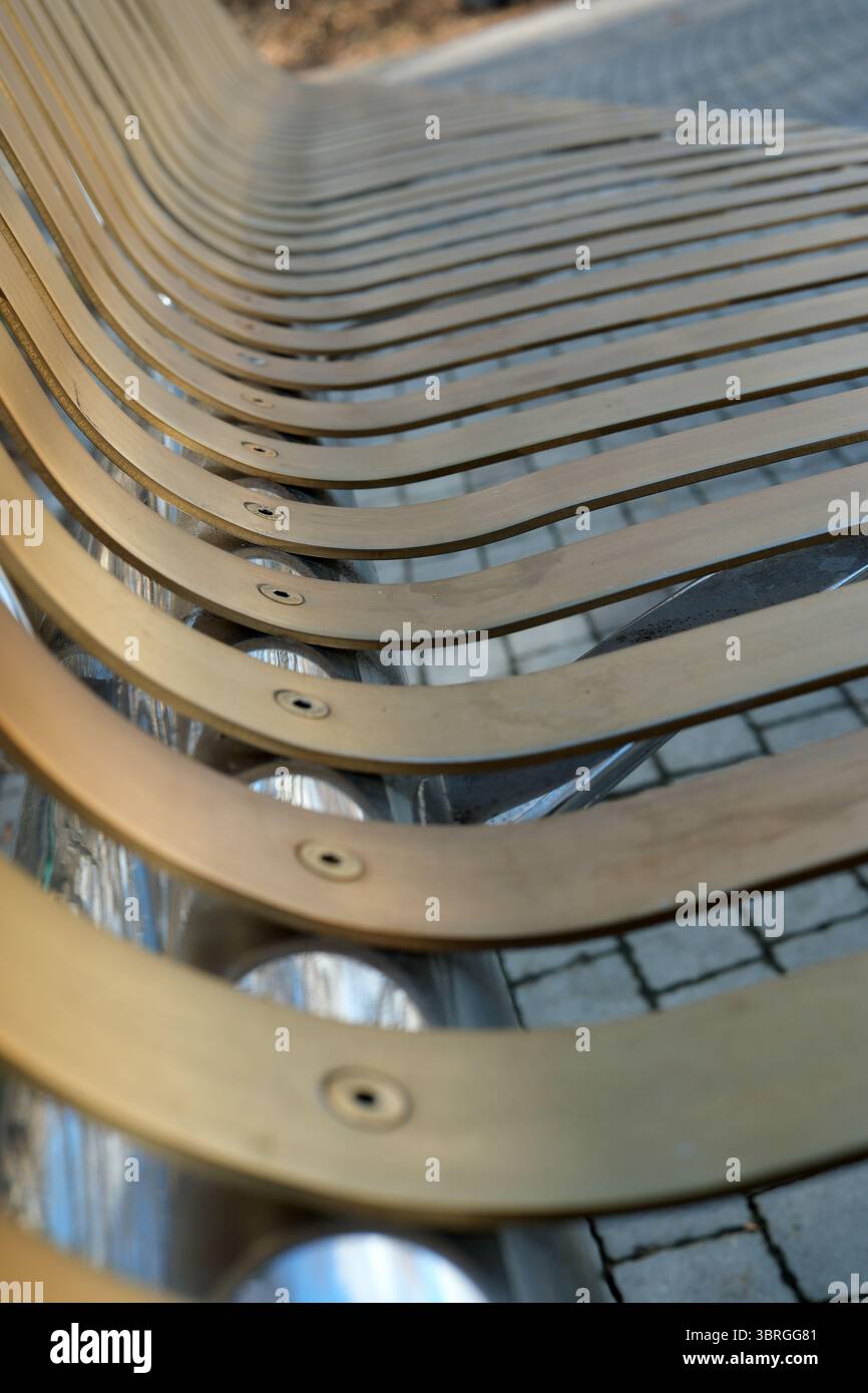 Curving lines of a minimalist bench shimmer under a bright sun ...