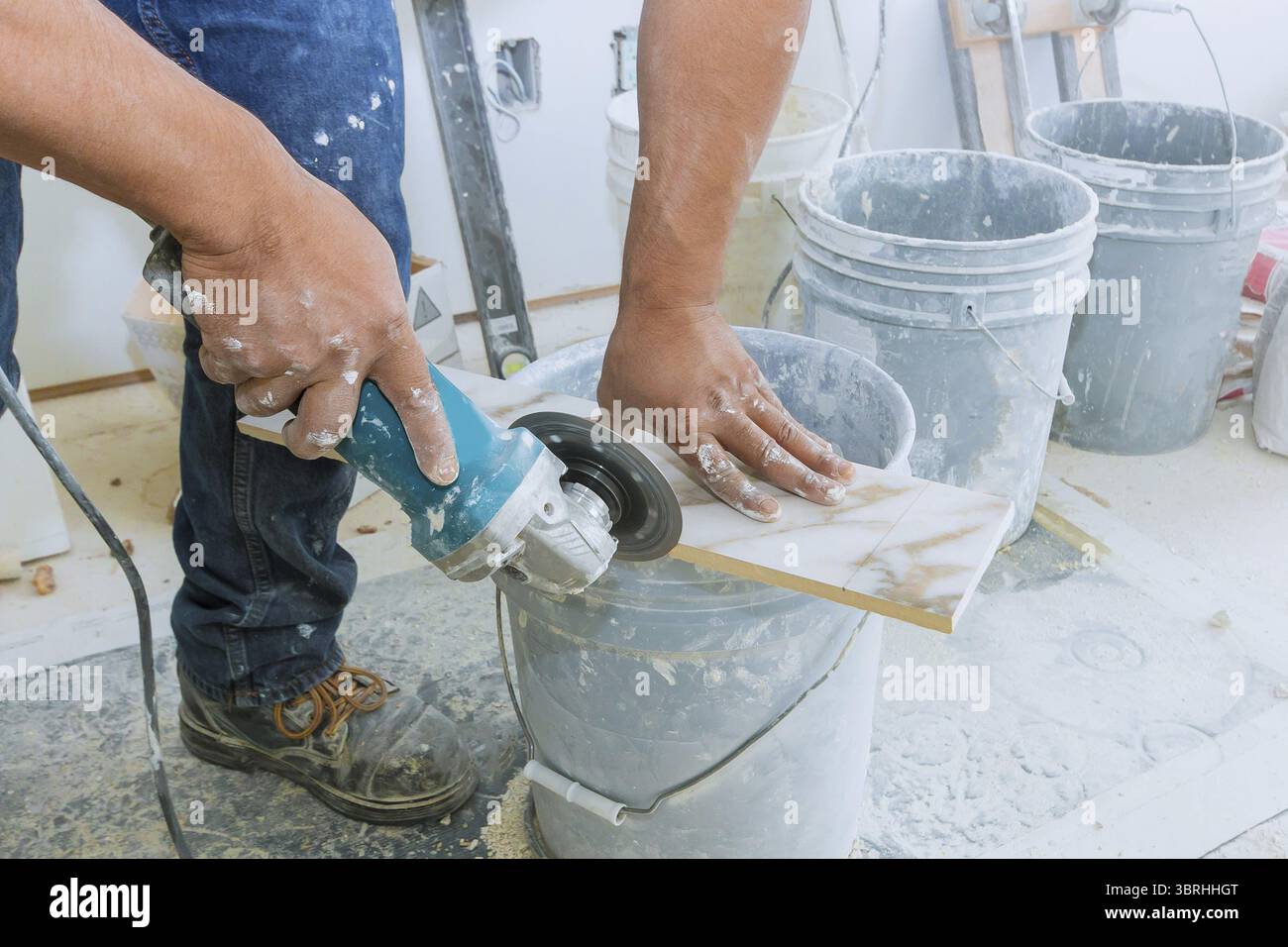 A construction worker cutting a tile using grinder round the ceramic ...