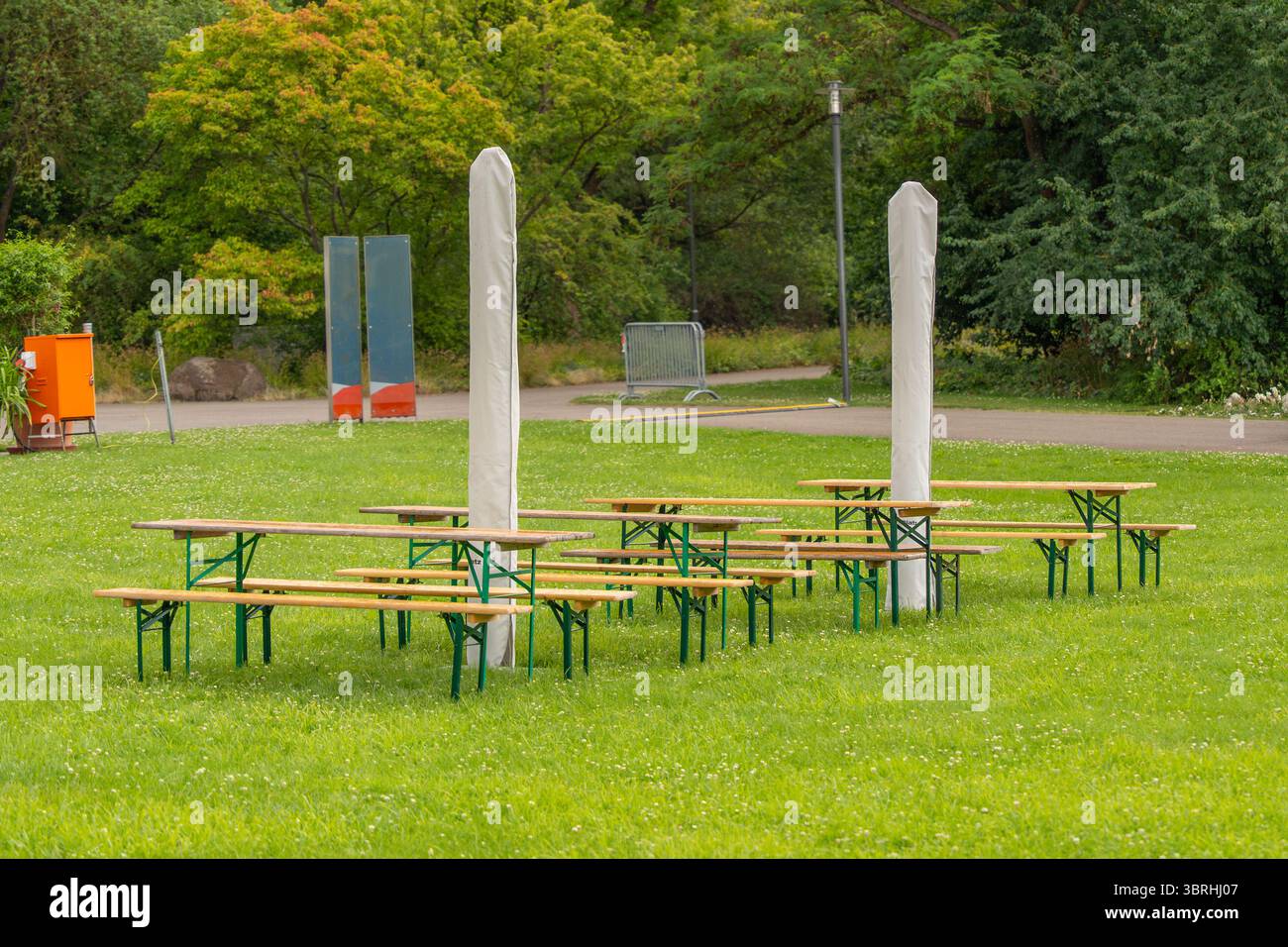 An arrangement of empty beer garden benches stands neatly on a green ...