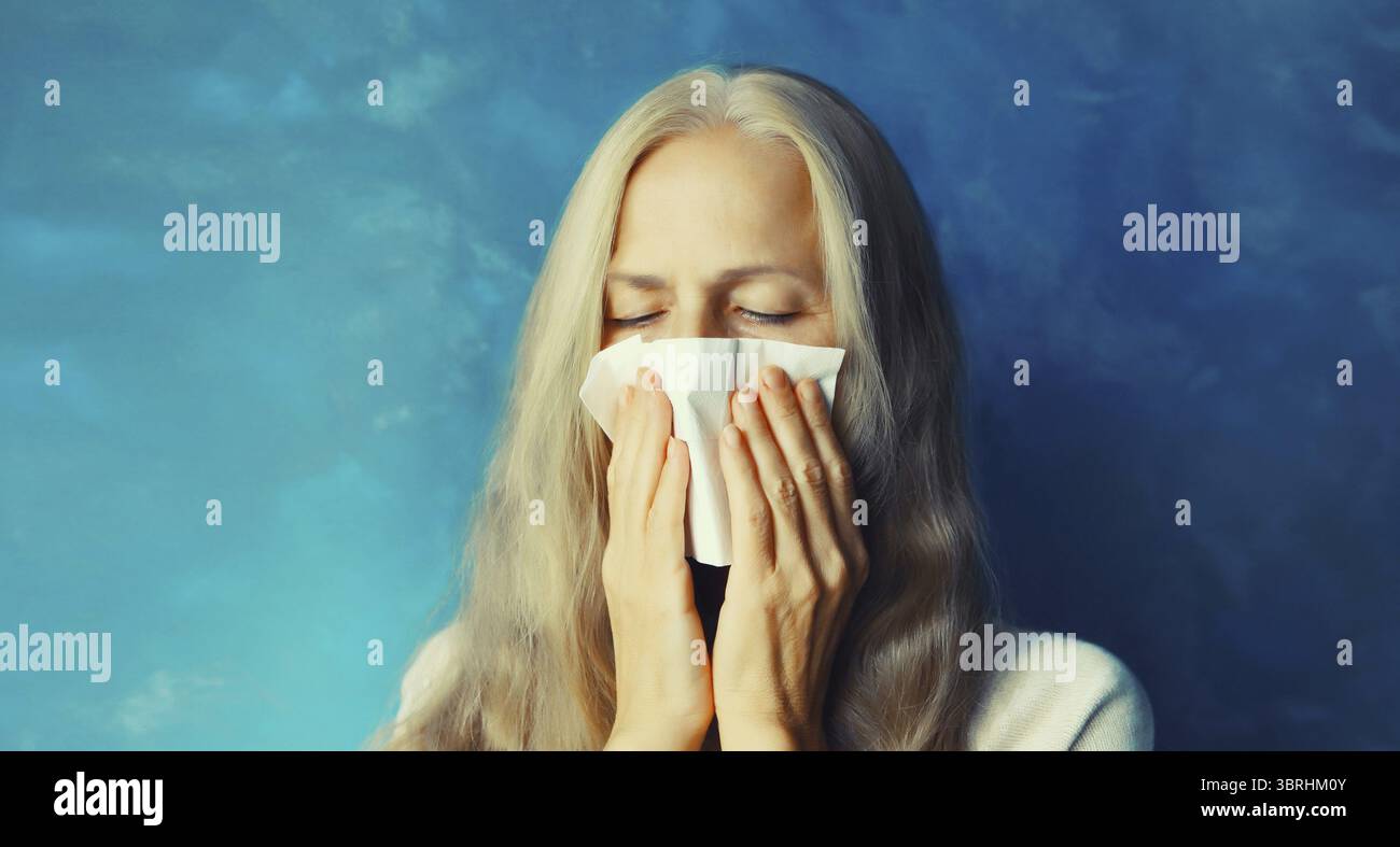 Sick exhausted middle aged woman sneezing blow nose using tissue at ...