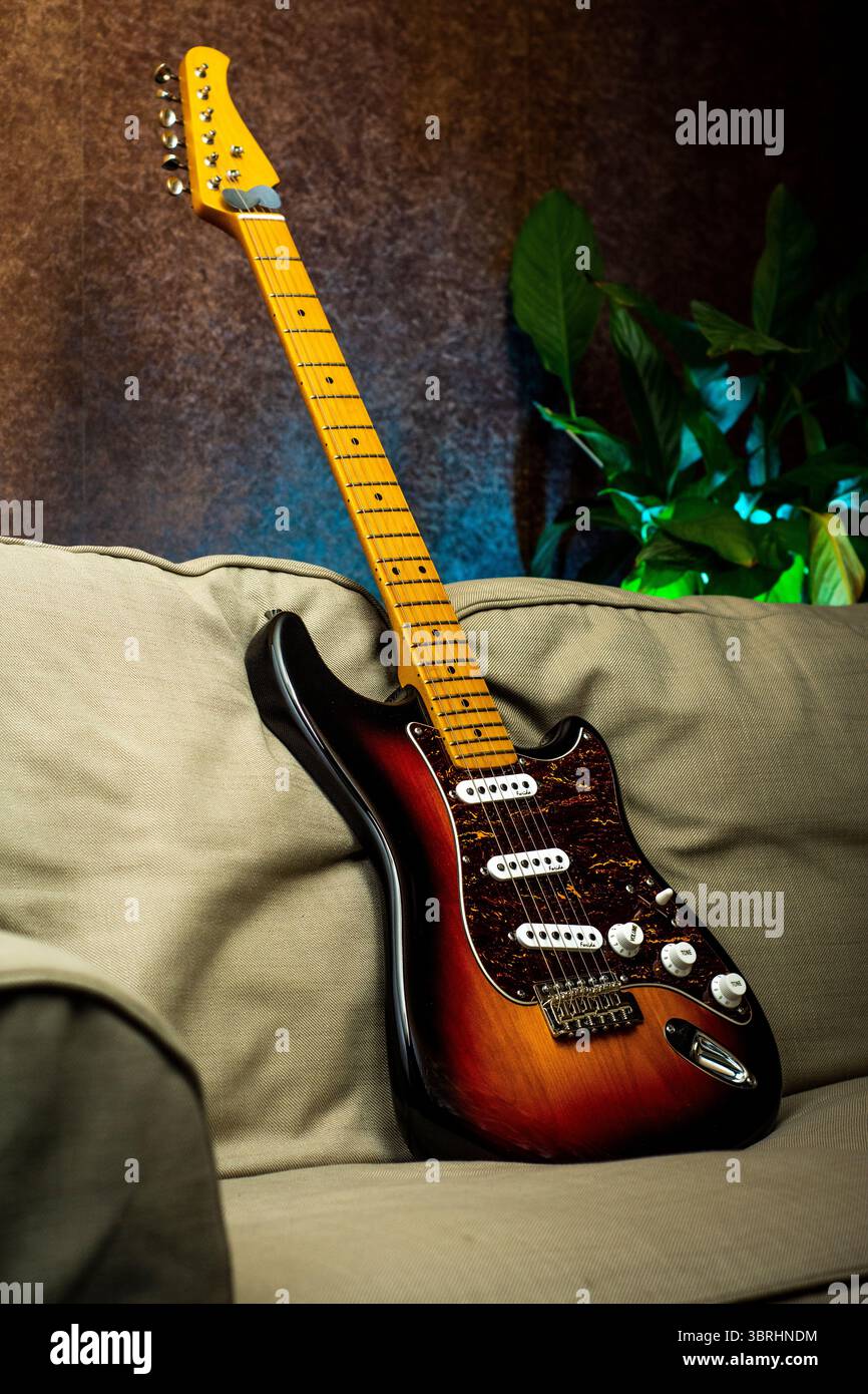 A Classic Sunburst Electric Guitar Rests On A Sofa Bathed In Warm
