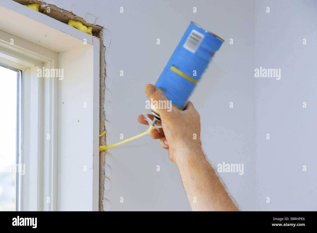 Hand holding polyurethane expanding foam glue gun applicator of windows ...