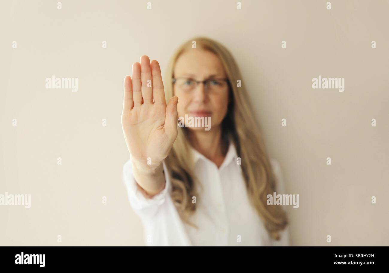 Upset middle-aged woman shows stop sign with palm of hand, refusal ...