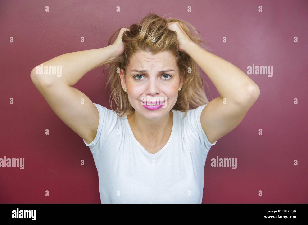 Concept of worry, woman with both hands on head on red background Stock ...