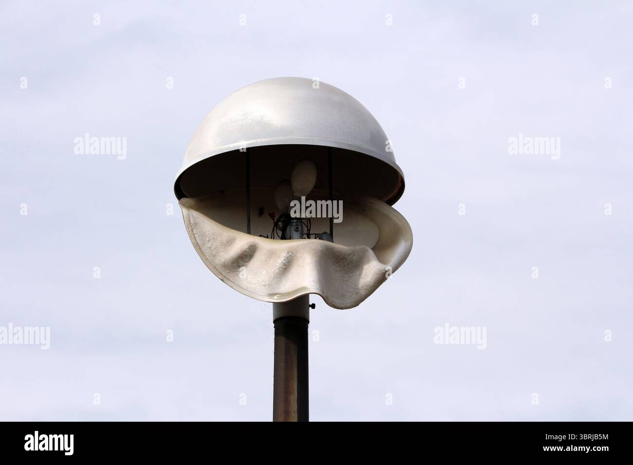 A street lamp features a white dome shade warped and melted, exposing ...