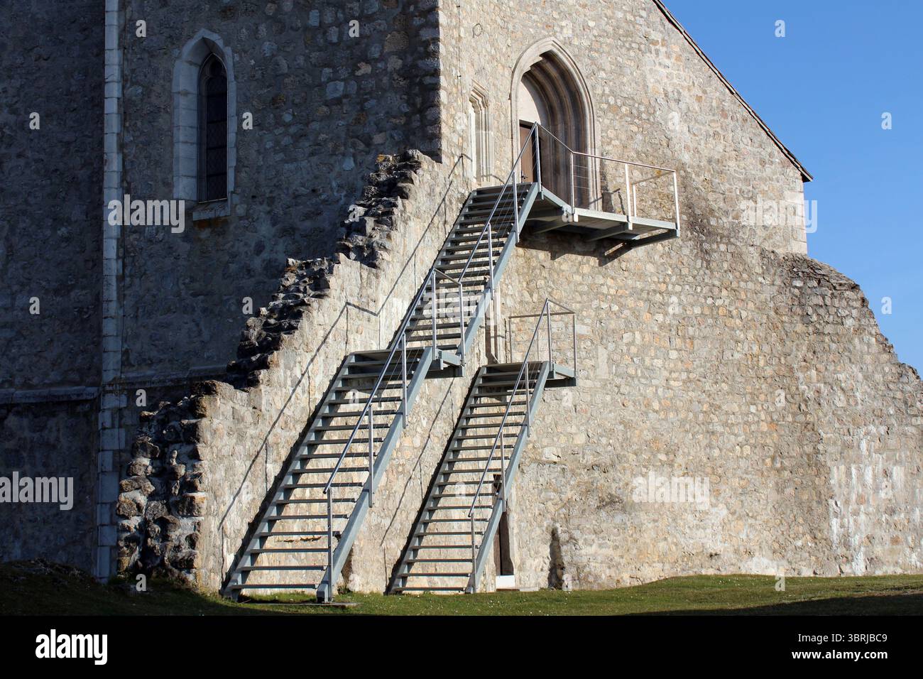 A medieval stone church features a striking modern metal staircase and ...