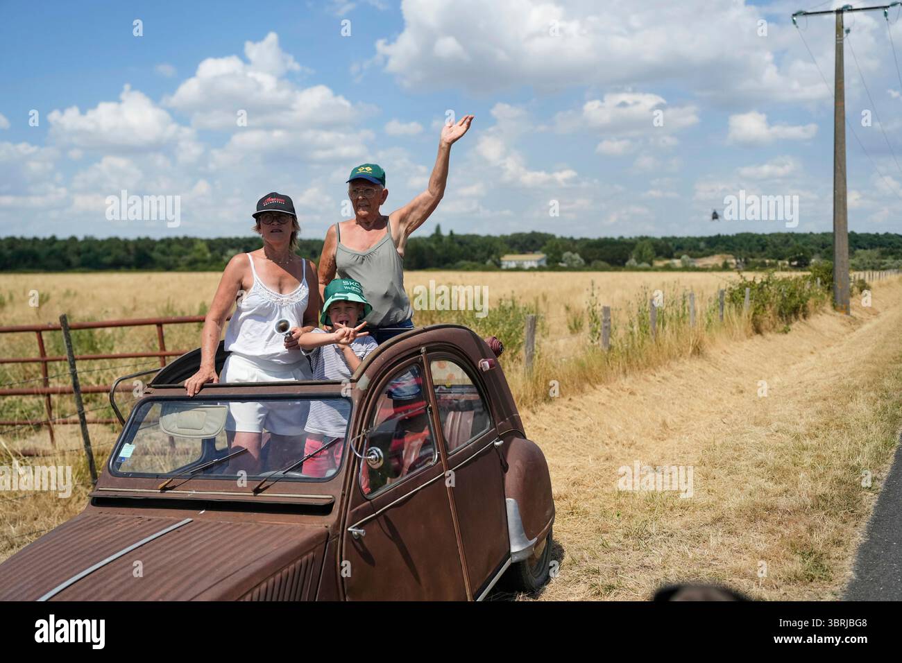 People wave from a Citroen 2CV classic car during the ninth stage of ...