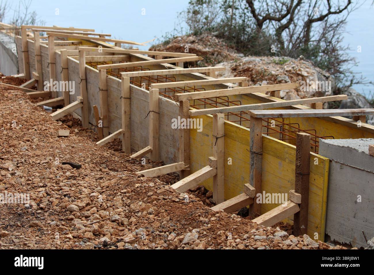 A row of wooden formwork panels reinforced with steel rebar lines a ...