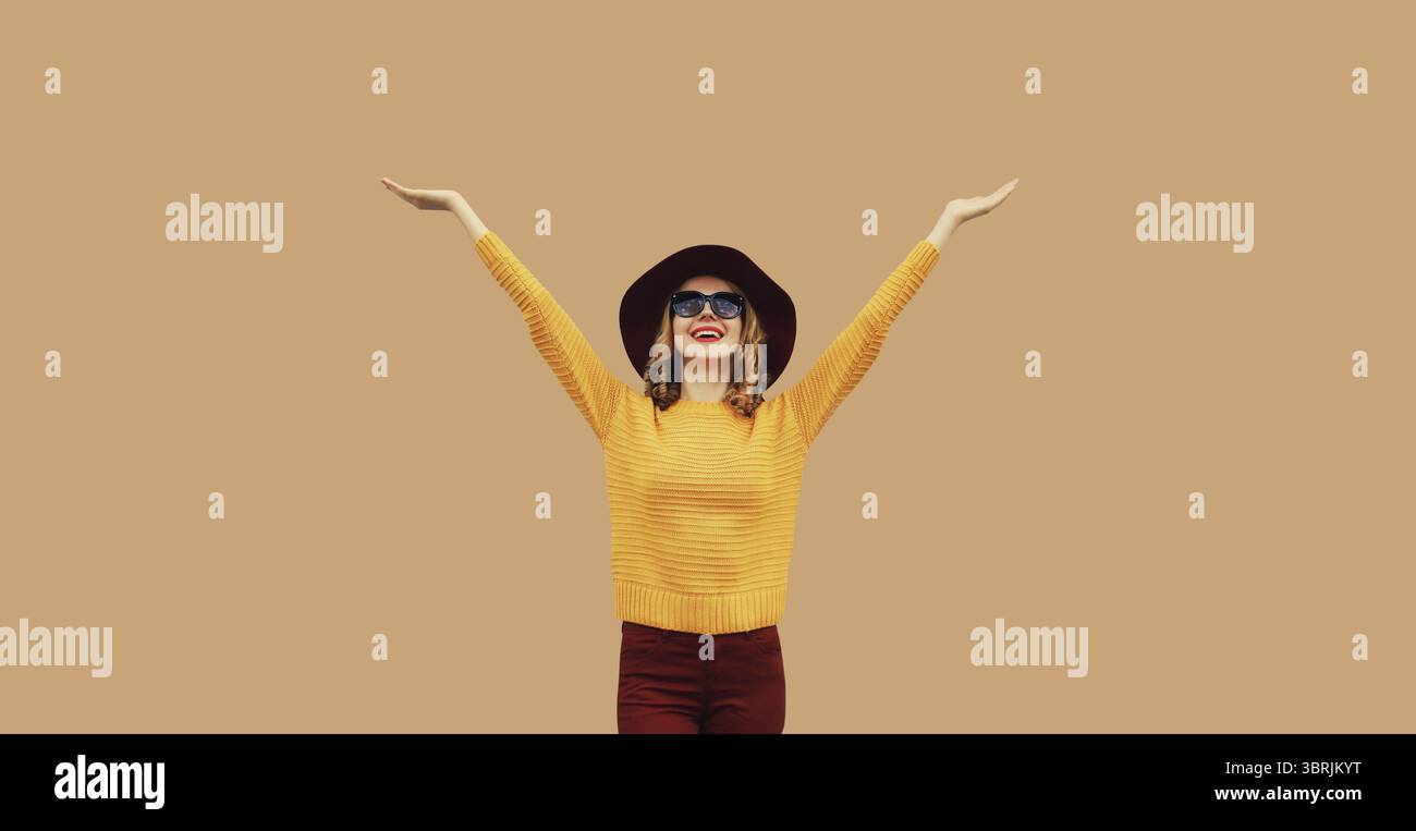 Cheerful happy laughing young woman raising her hands up wearing hat ...