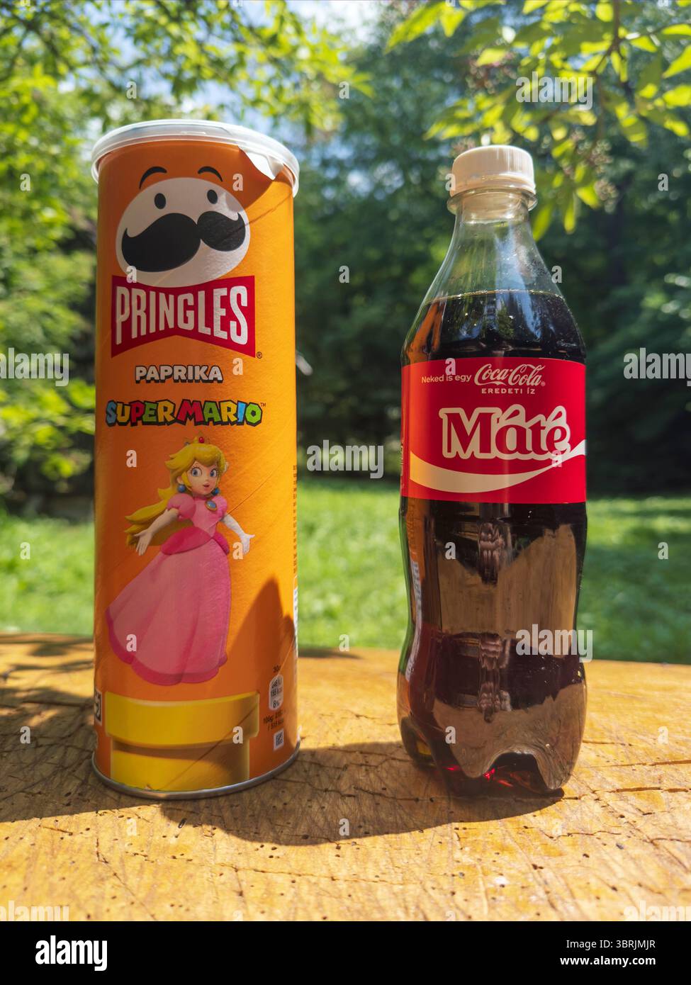 snack lunch on garden table consisting of tube of paprika pringles and ...