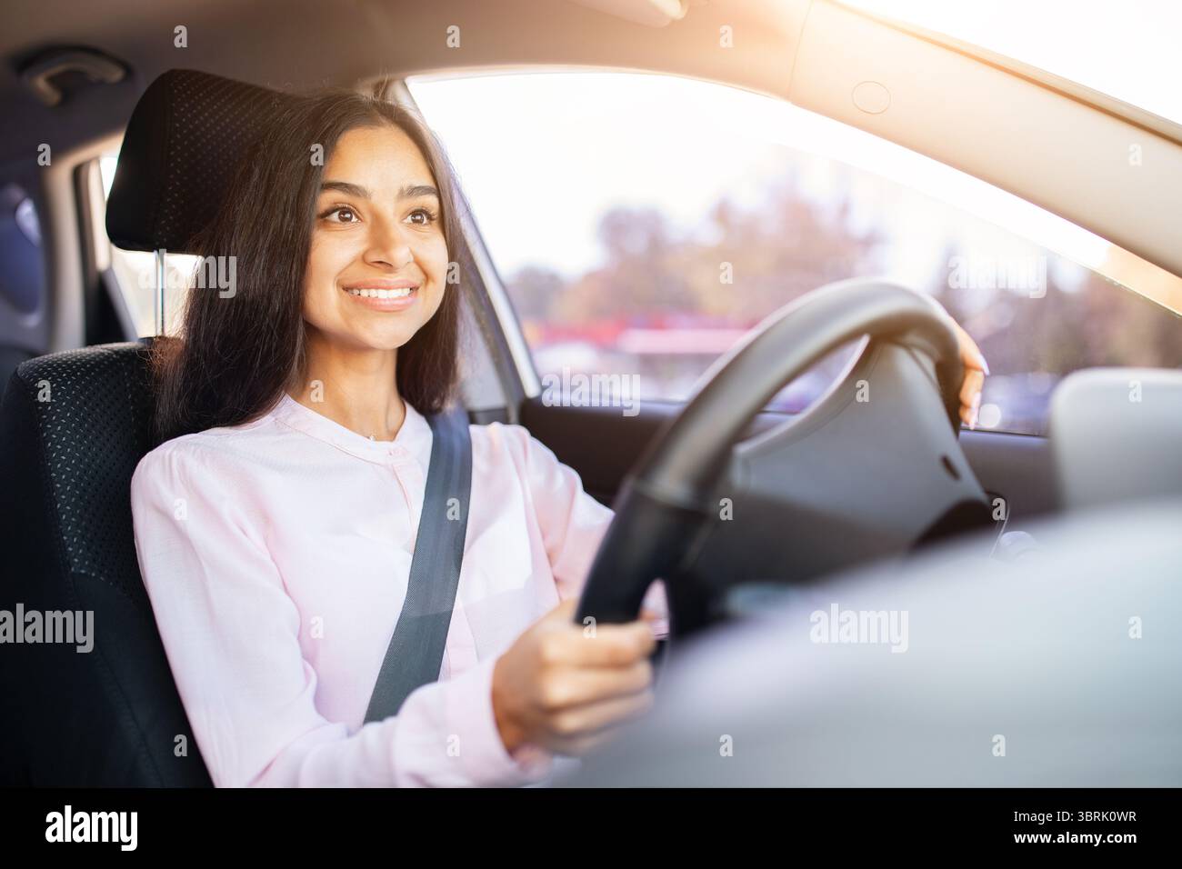 Young Indian woman smiling confidently while driving car, hands on ...