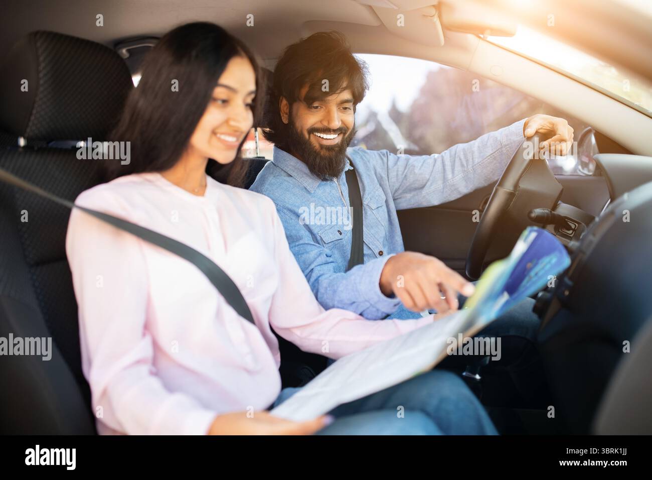 Man and woman happily planning route using map while sitting in car ...