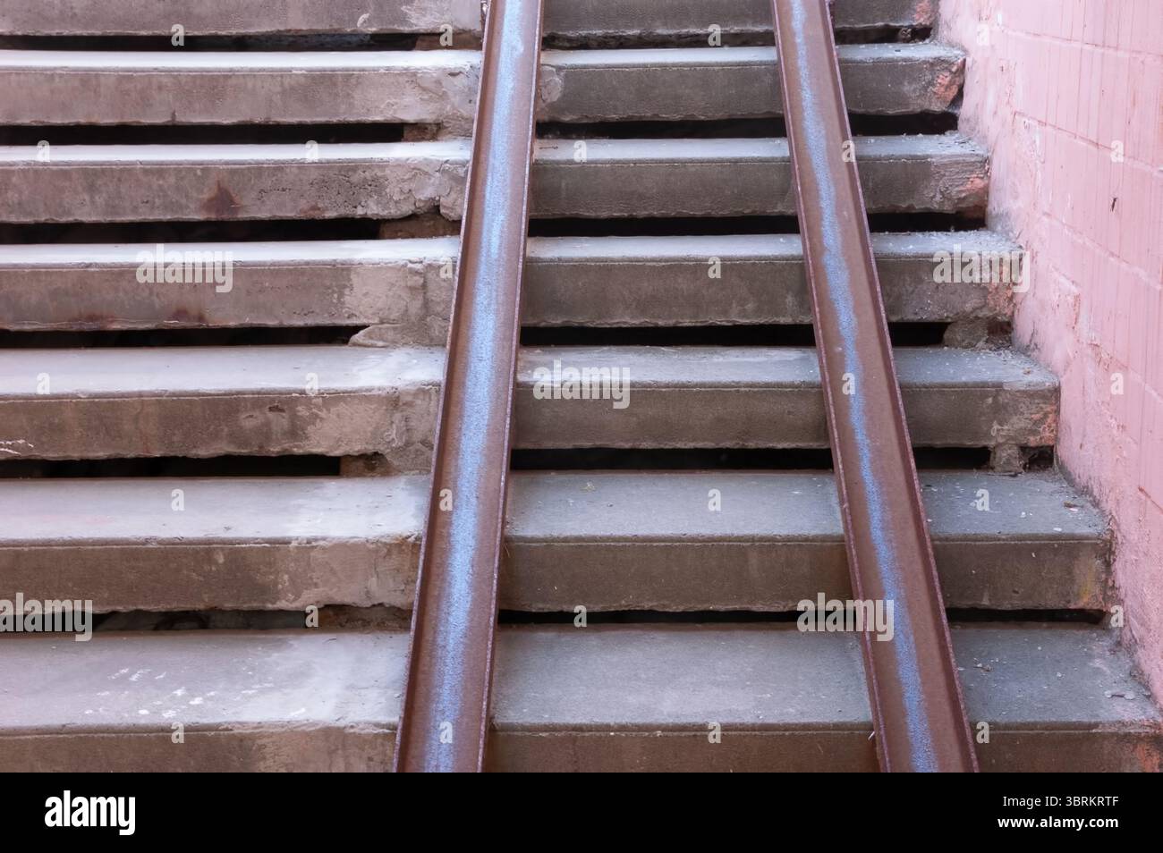 Old concrete stairs in an underpass, worn and roughly repaired. Two ...