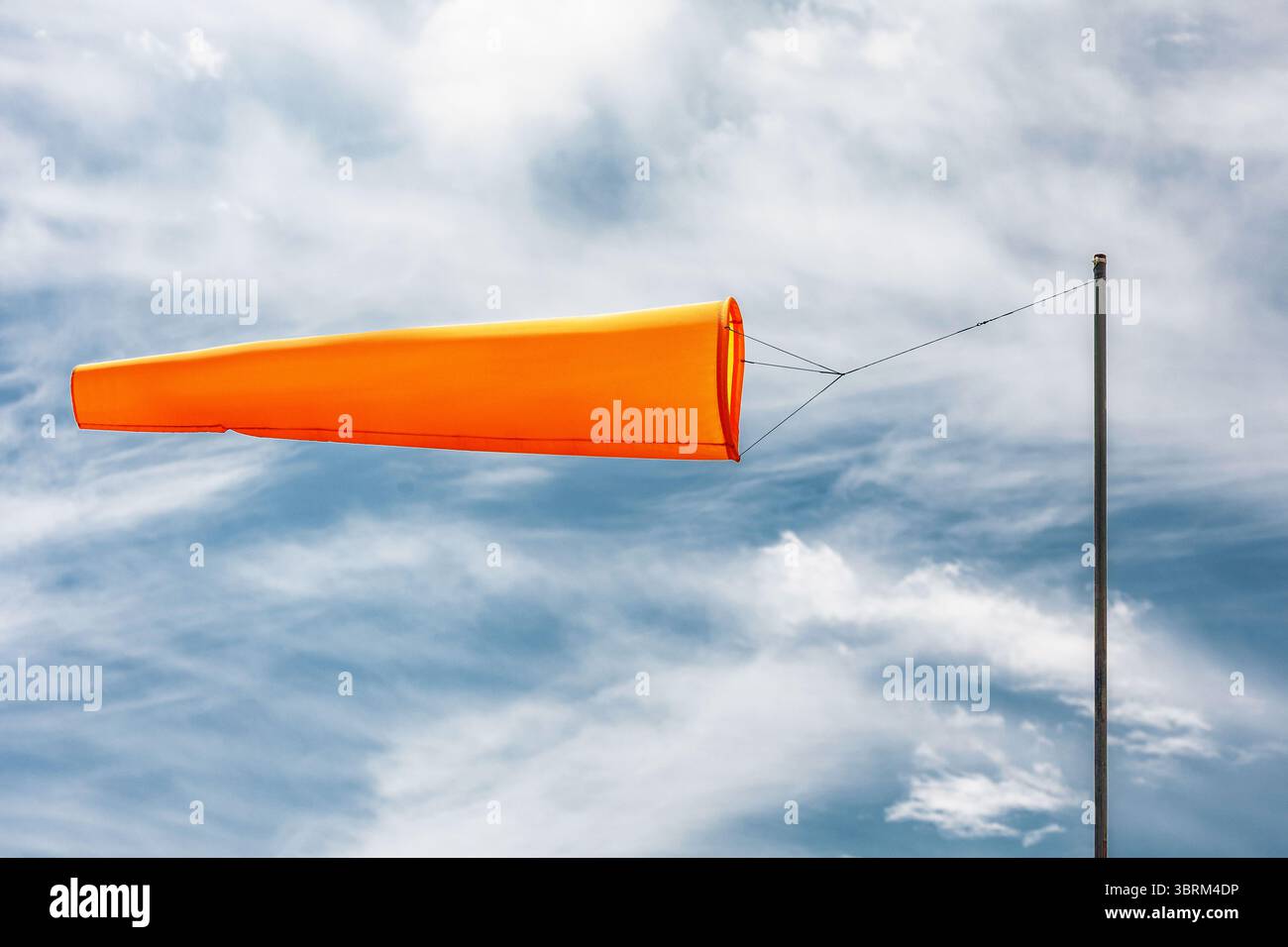 Orange windsock is attached to a pole and showing the wind direction ...