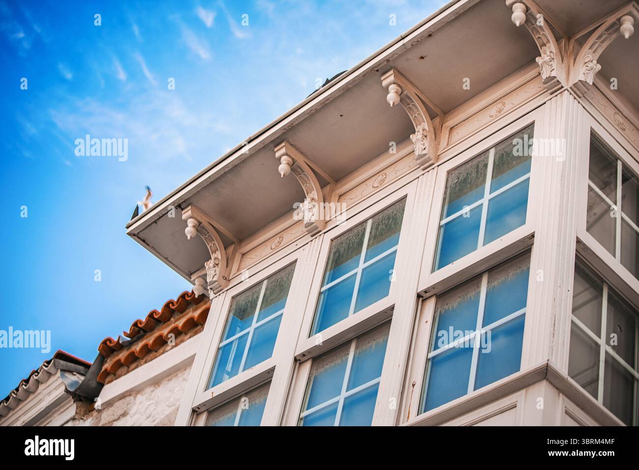 Low angle view of a white vintage bay window reflecting the blue sky ...