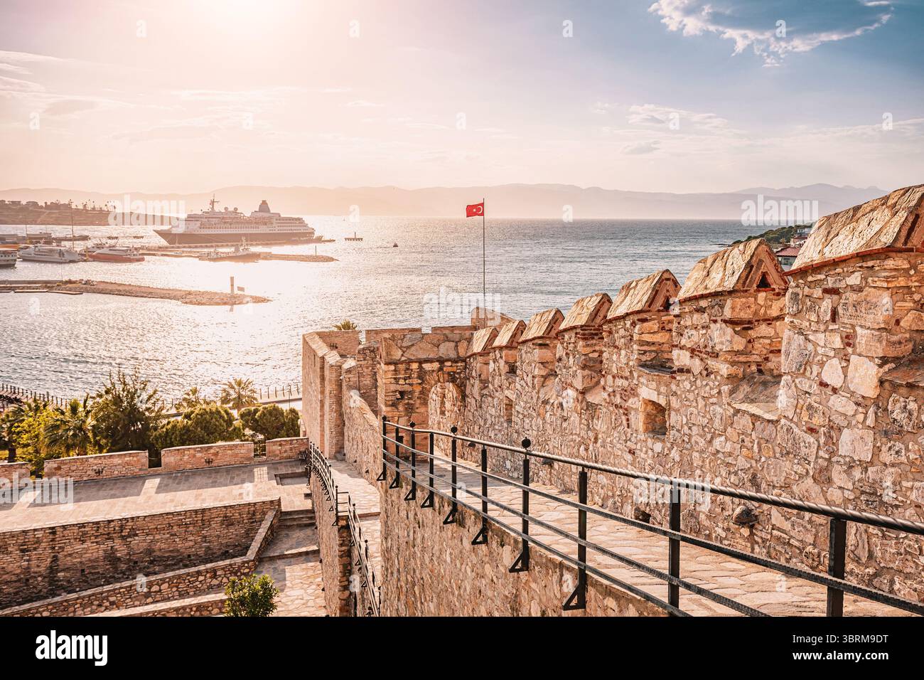 Turkish flag waving over ramparts of Cesme Castle with cruise ship ...