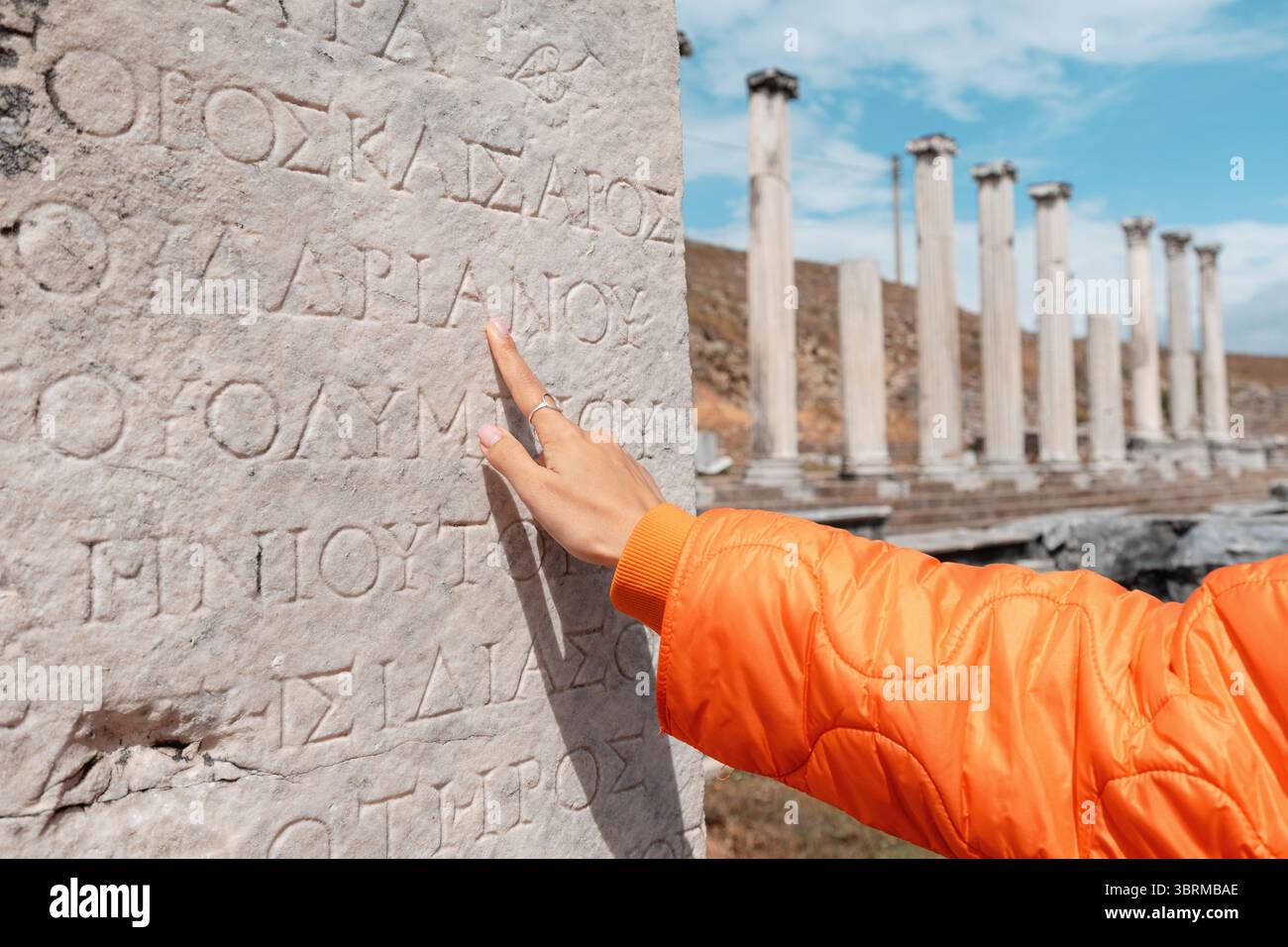 Tourist pointing finger at ancient greek inscription carved on a marble ...