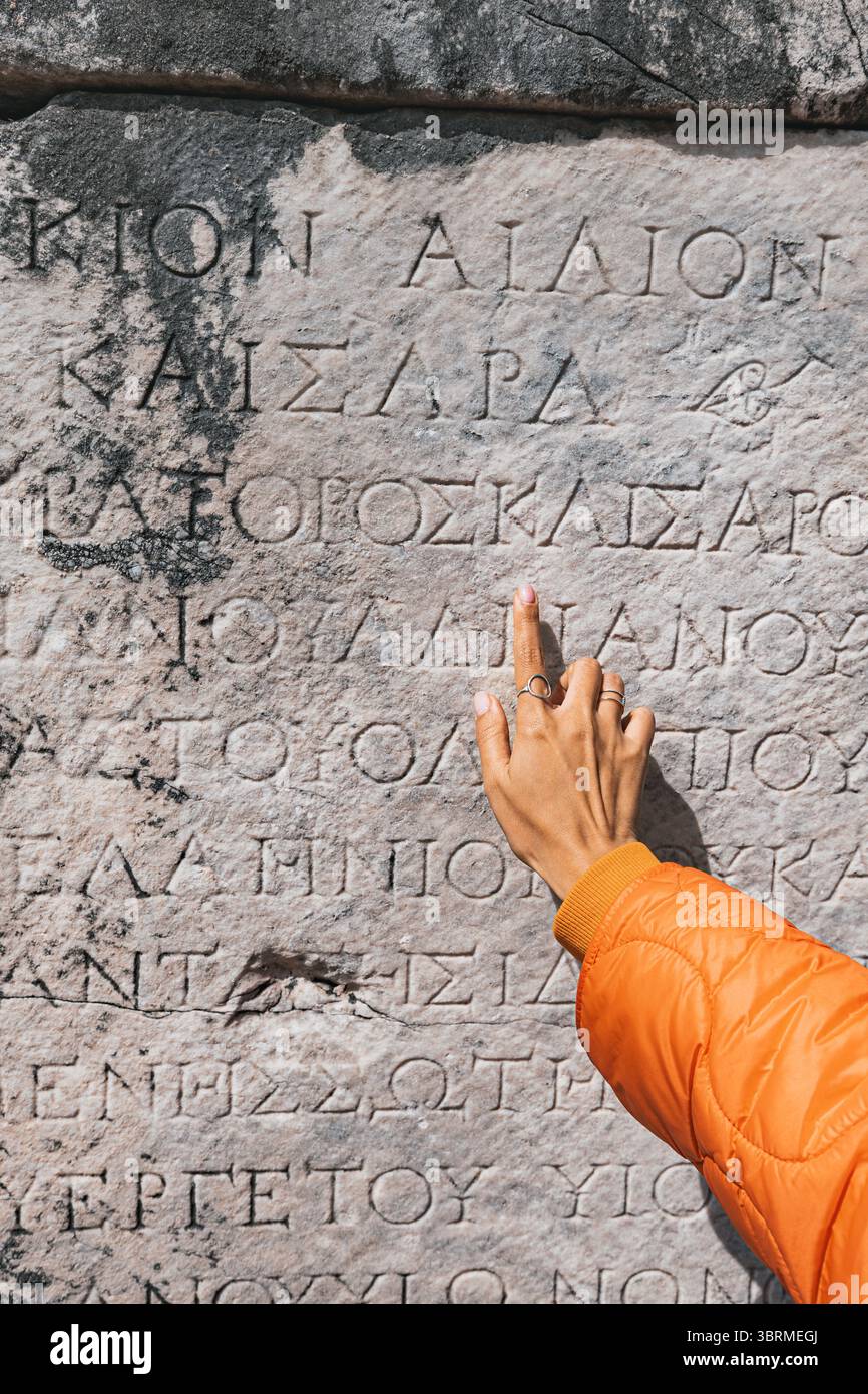 Tourist pointing finger at ancient greek inscription carved on a marble ...