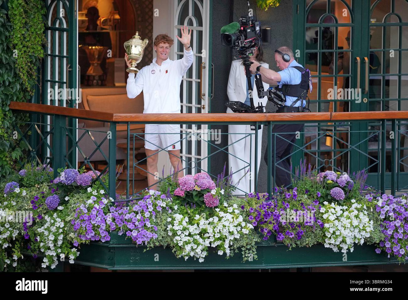 Italy's Jannik Sinner shows the trophy from the balcony of Centre Court ...