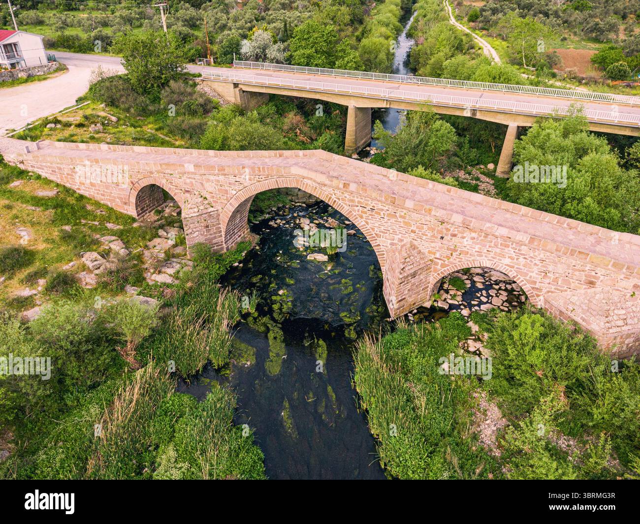 Ancient stone bridge stands majestically, arching over a river winding ...