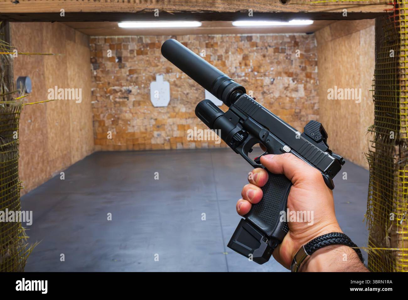 A shooter's hand holds a modified tactical pistol with a silencer ...