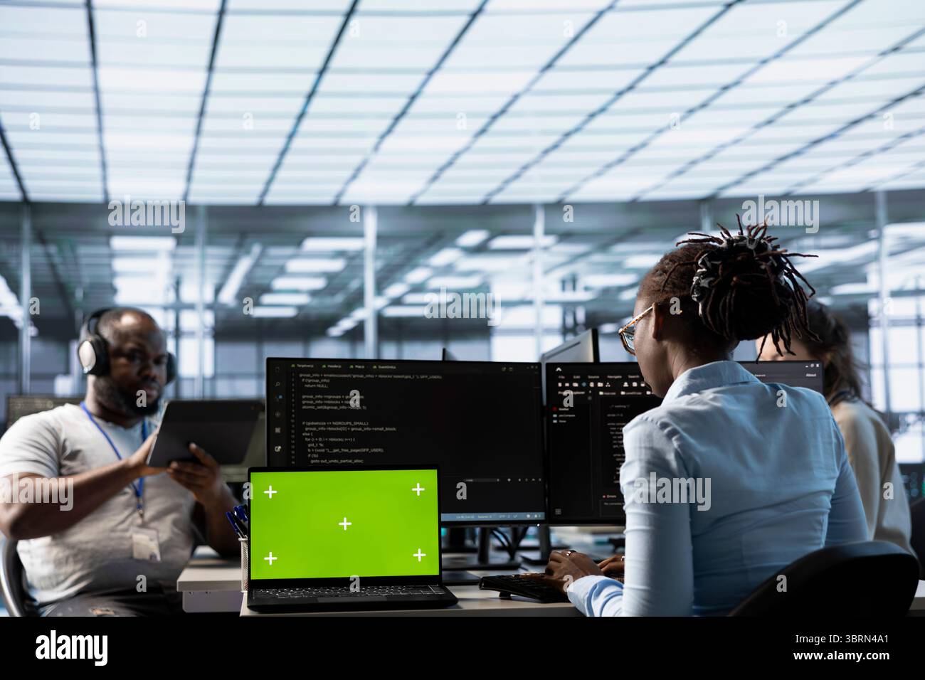 Green screen laptop in data center in front of IT support specialists ...