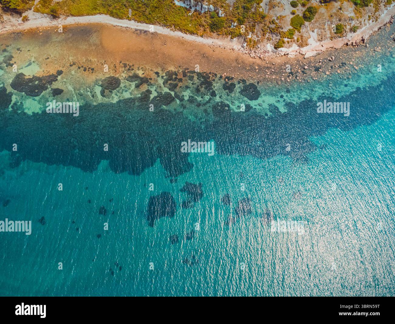 Crystal clear turquoise water gently washing a rocky coastline and a ...