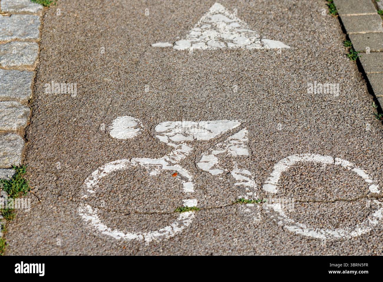 German Close-up of a worn asphalt bike lane with white painted bicycle ...