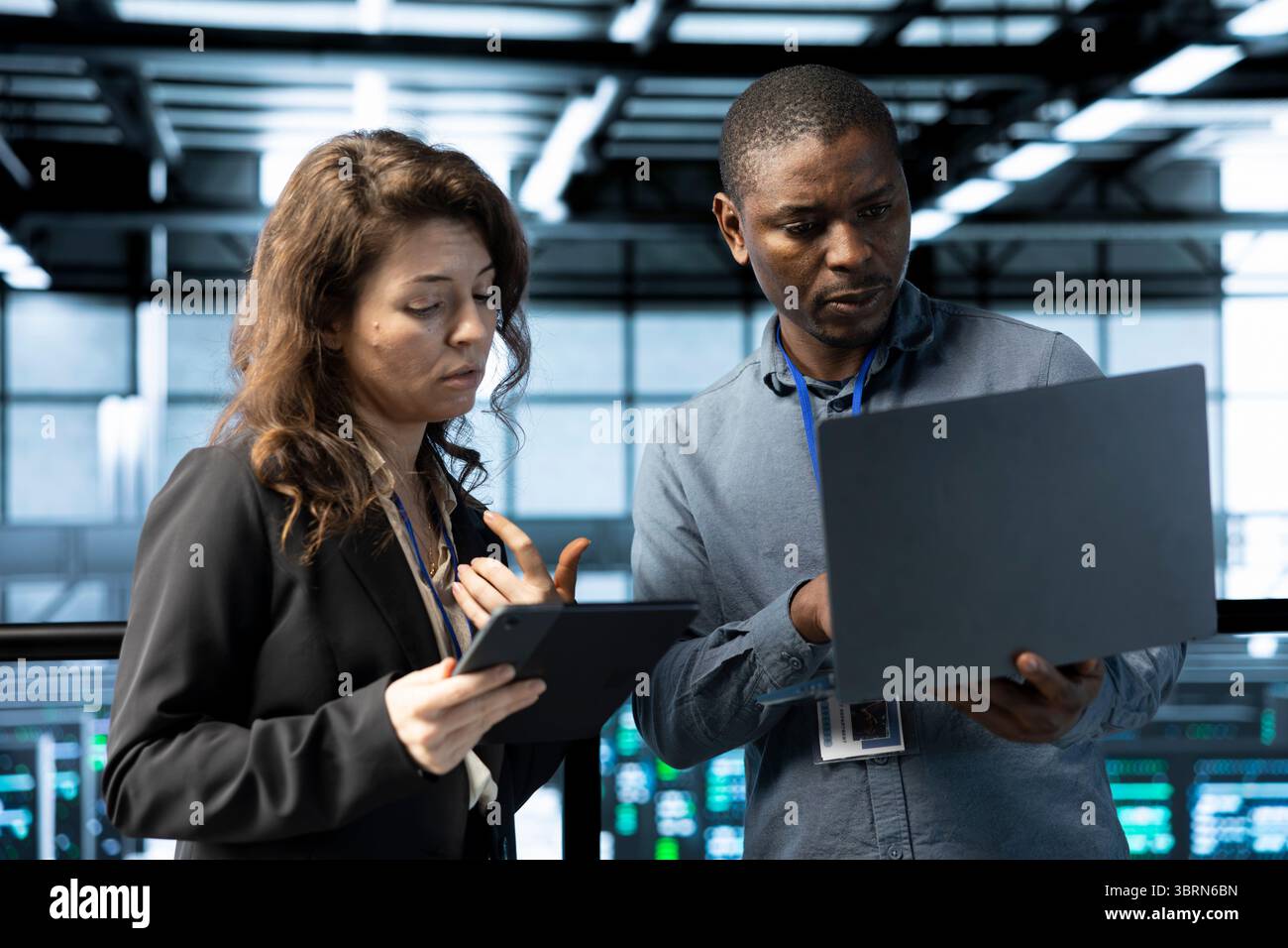 Programmers in data center using laptop and tablet, executing security patches, securing ...