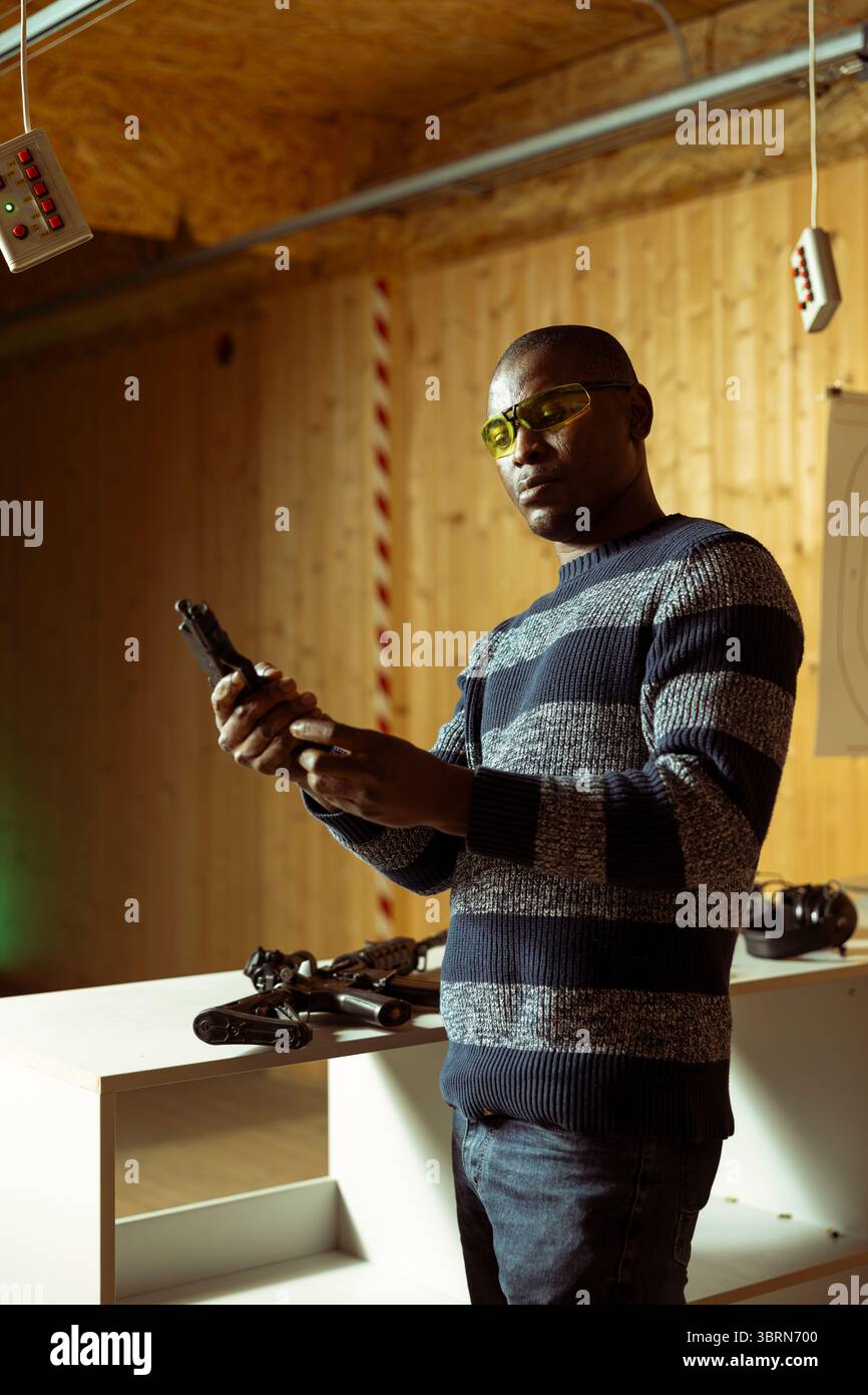 Man wearing protective eyewear reloading handgun in indoor shooting ...