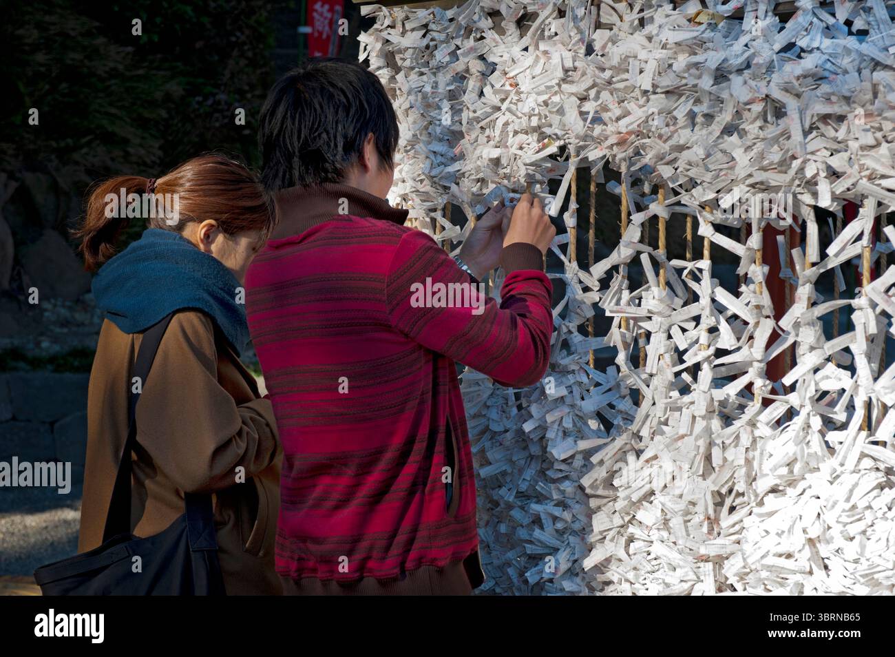 A couple tying an "omikuji" paper oracle, either good fortune or bad ...