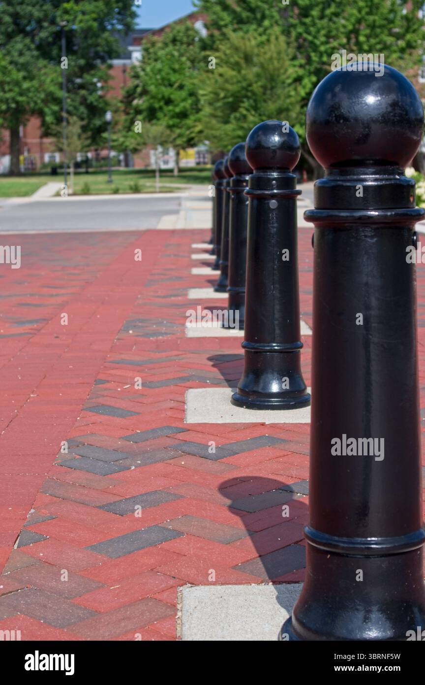 Black metal bollards on a brick paver walkway Stock Photo - Alamy