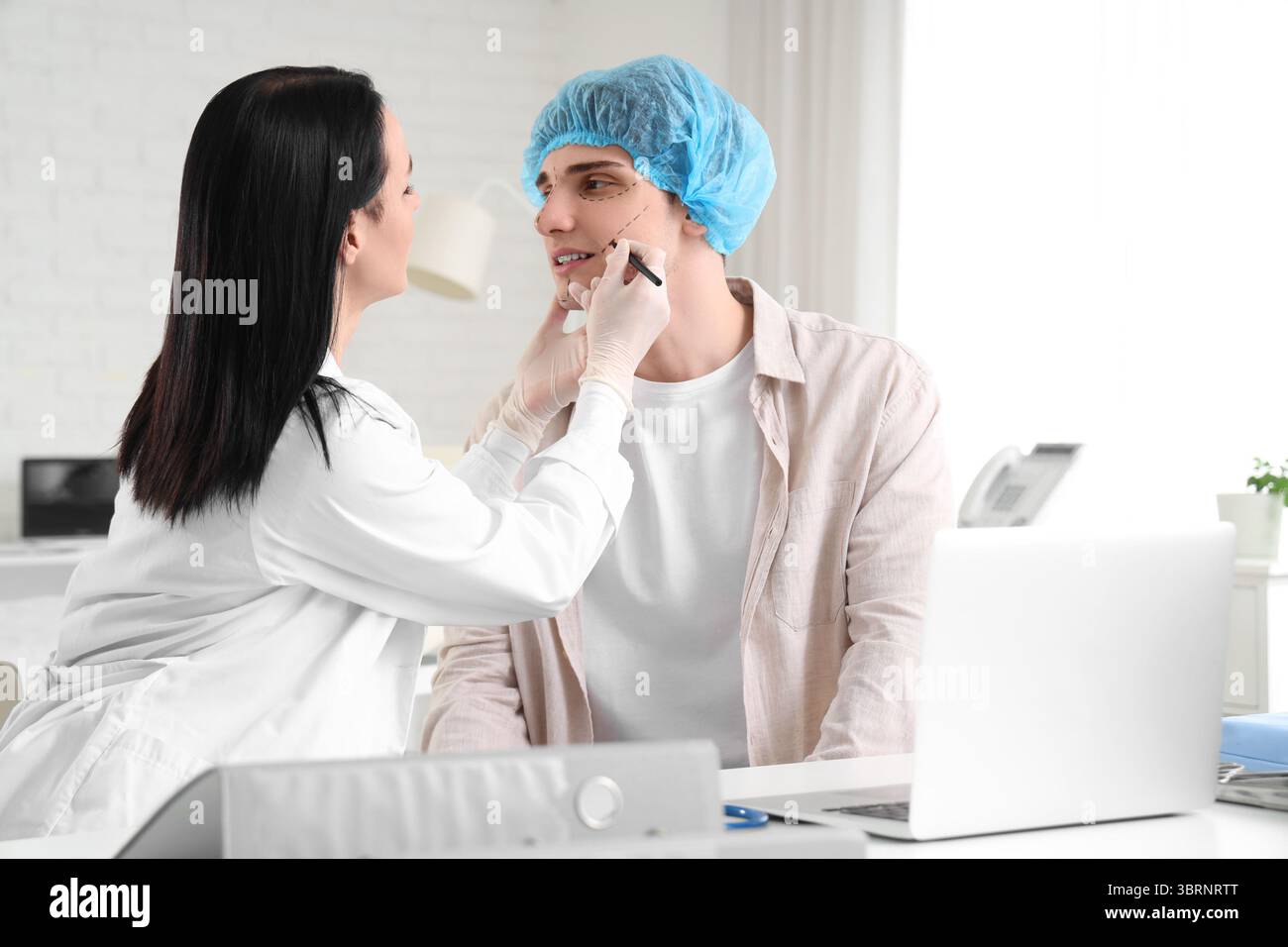 Female plastic surgeon marking man's face in clinic Stock Photo - Alamy