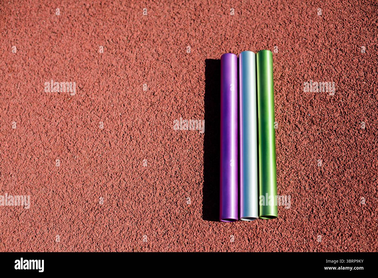 Three relay batons on the ground Stock Photo - Alamy