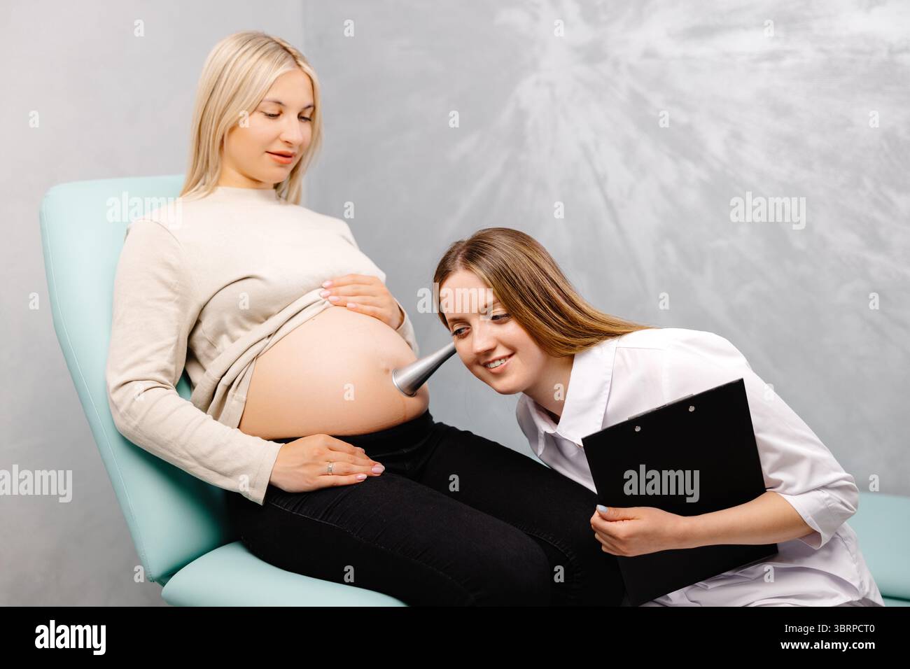 A gynecologist leans a stethoscope to a pregnant woman's belly and ...