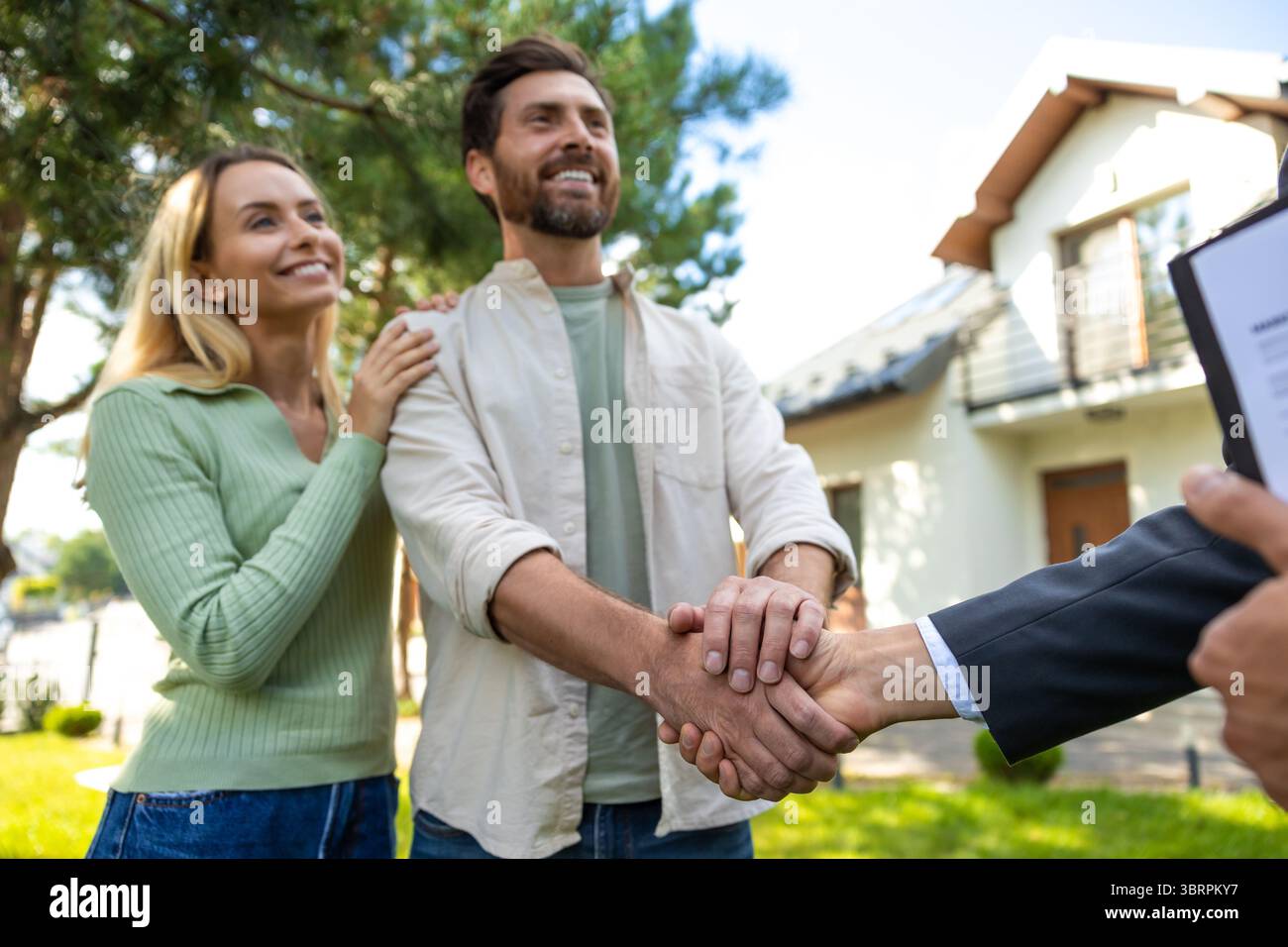 Couple shaking hands with real estate agent outside modern home Stock ...