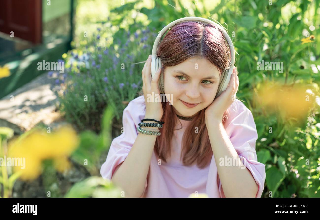 Teenager enjoying music in a garden setting, wearing wireless ...