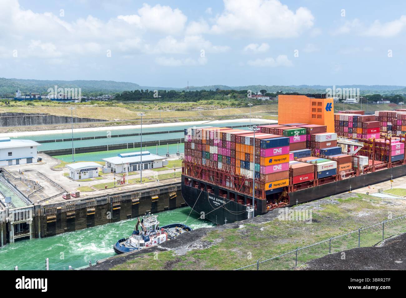 Colon, Panama - April 13, 2024: A tugboat guides a container ship ...