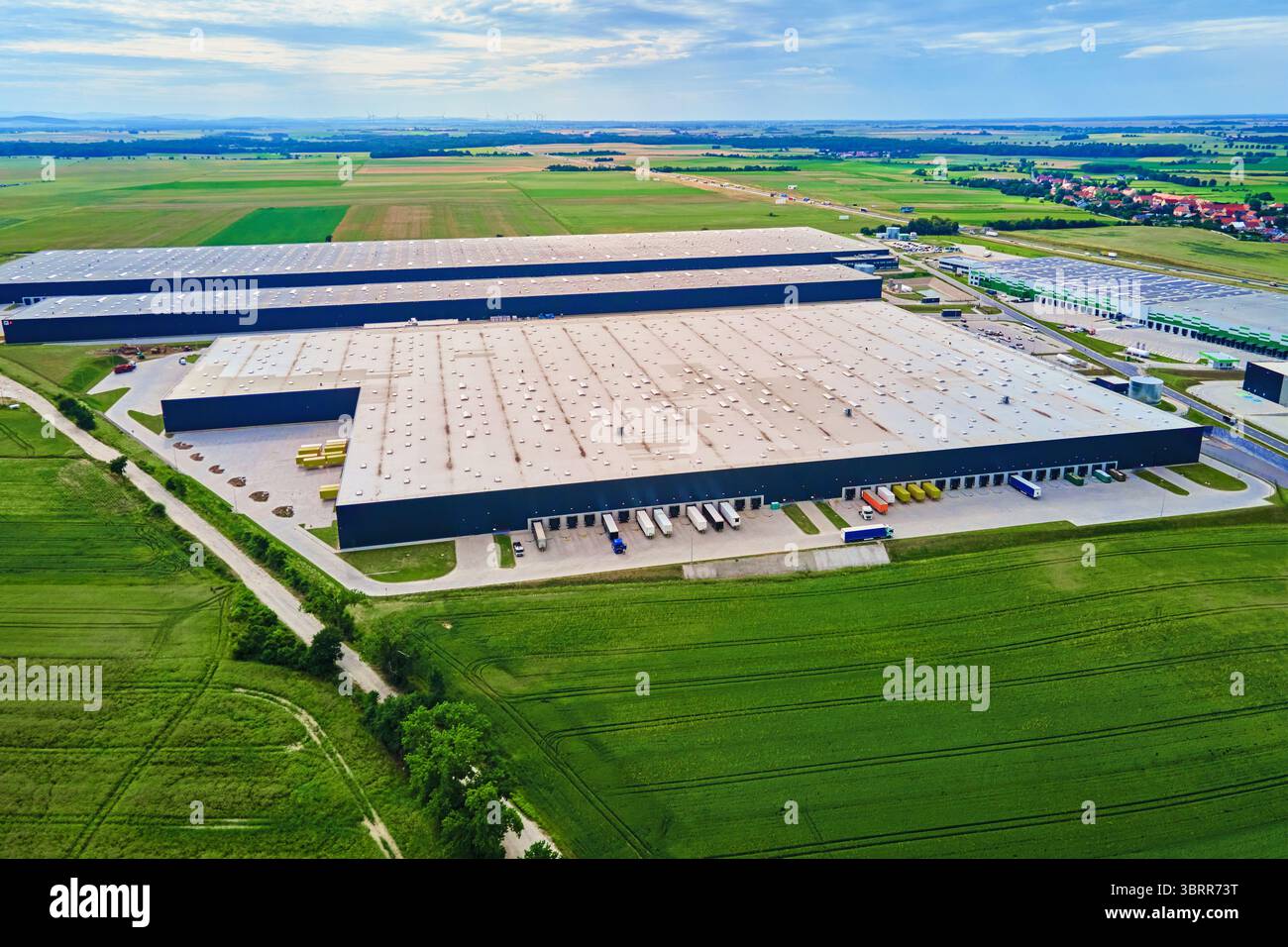 Large modern warehouse with loading docks and parked trucks surrounded ...