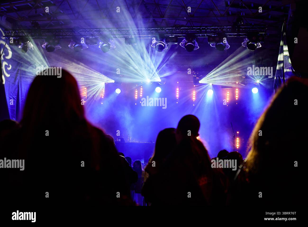 Crowd enjoying concert with bright lights and smoke on stage ...