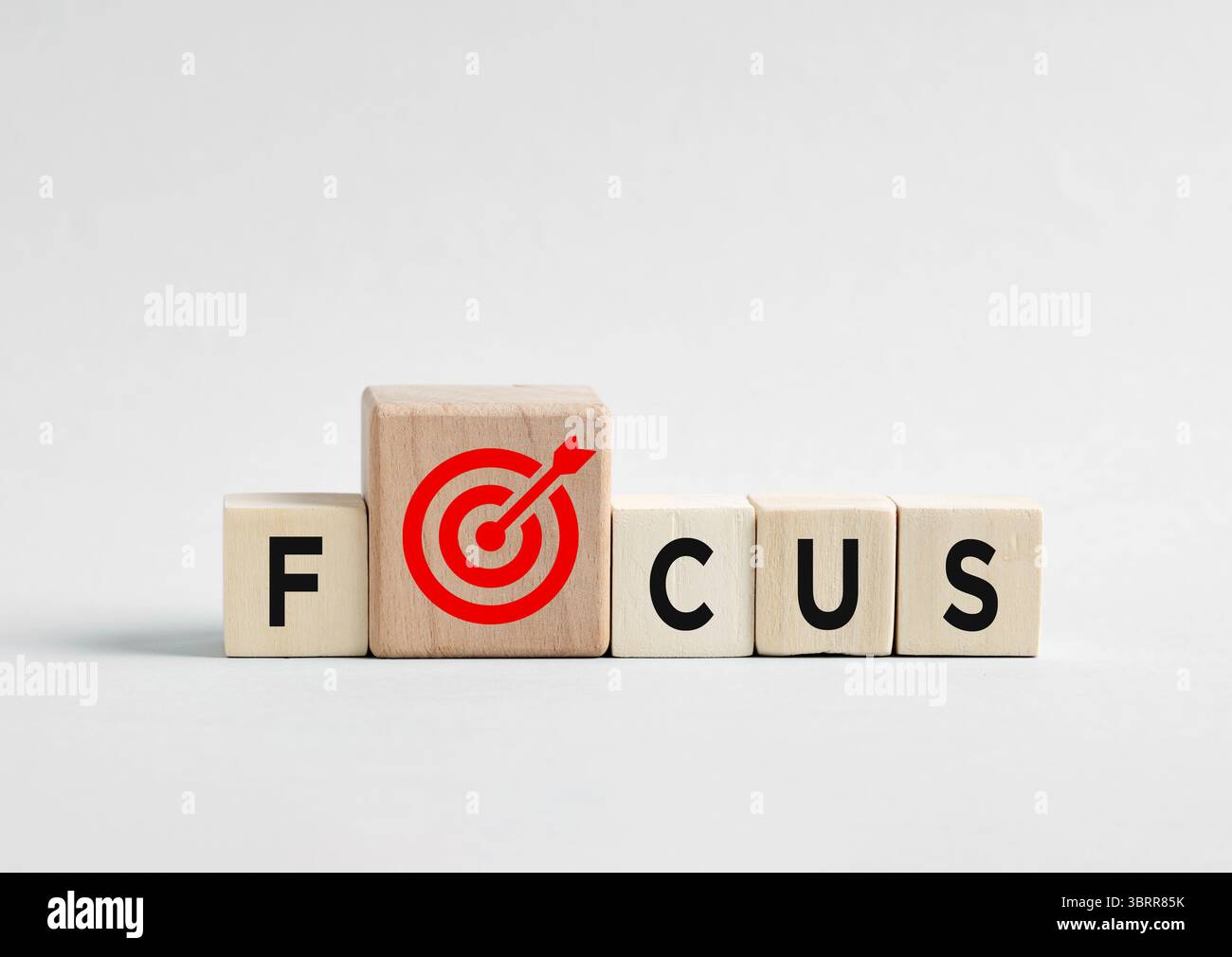 Wooden cubes composing the word focus and a red target on a white ...