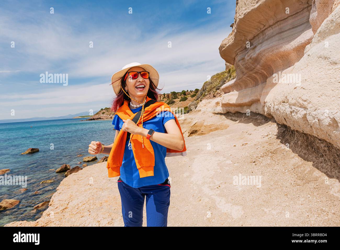 Happy tourist running joyfully across rocky cliffs by the sea ...
