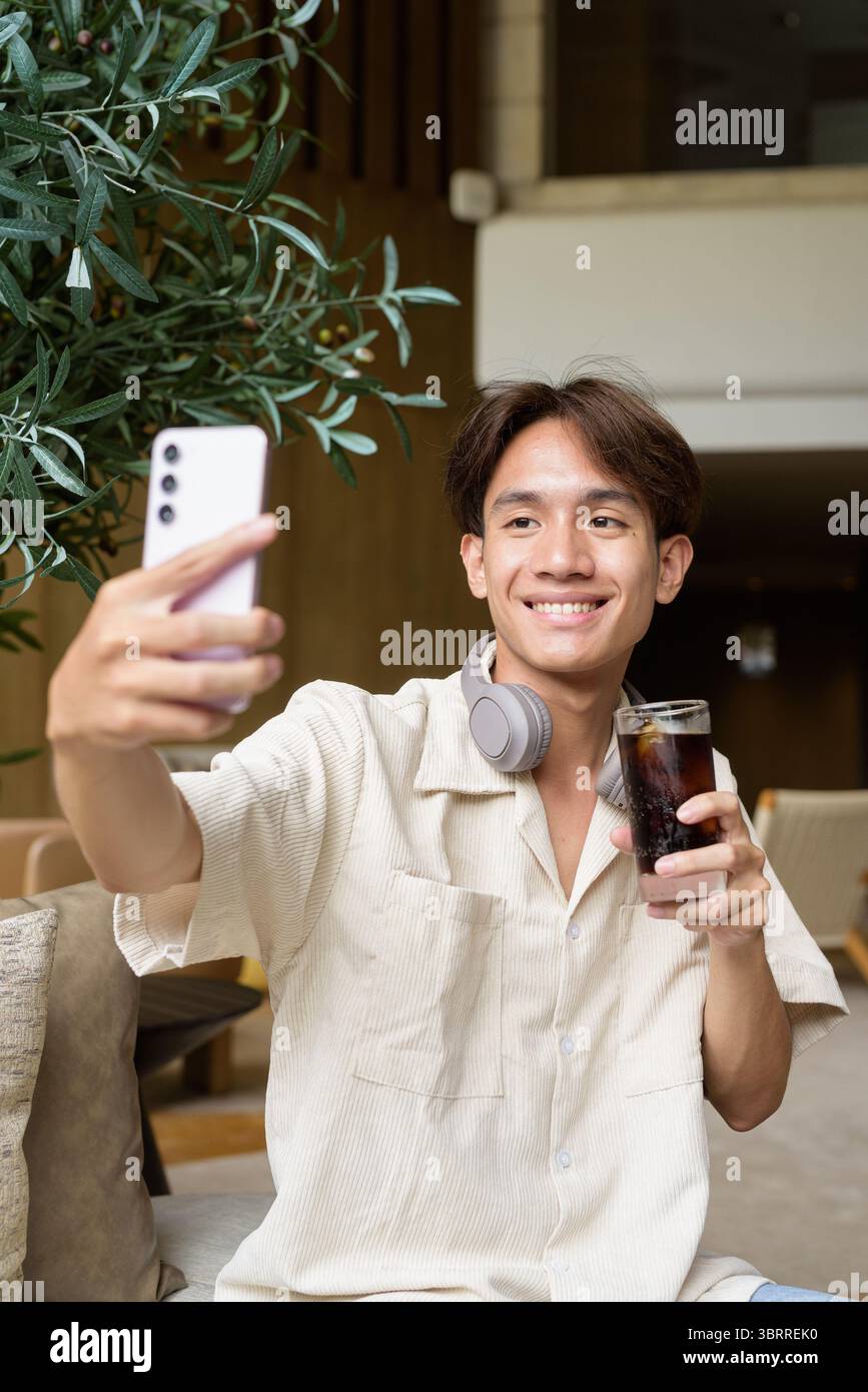Non binary cute Asian student man sitting in modern coffee shop Stock ...