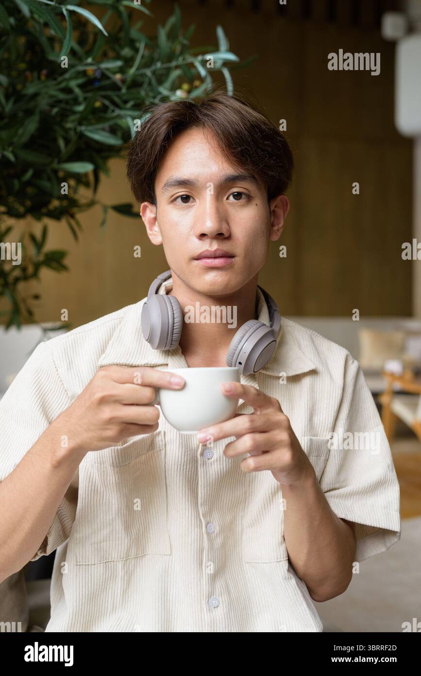 Non binary cute Asian student man sitting in modern coffee shop Stock ...