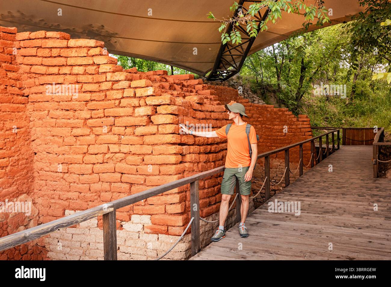 Tourist exploring ancient Troy ruins, gently touching a weathered red ...