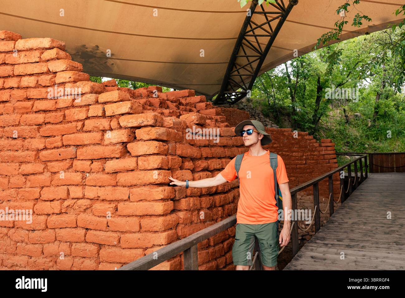 Tourist exploring ancient Troy ruins, gently touching a weathered red ...
