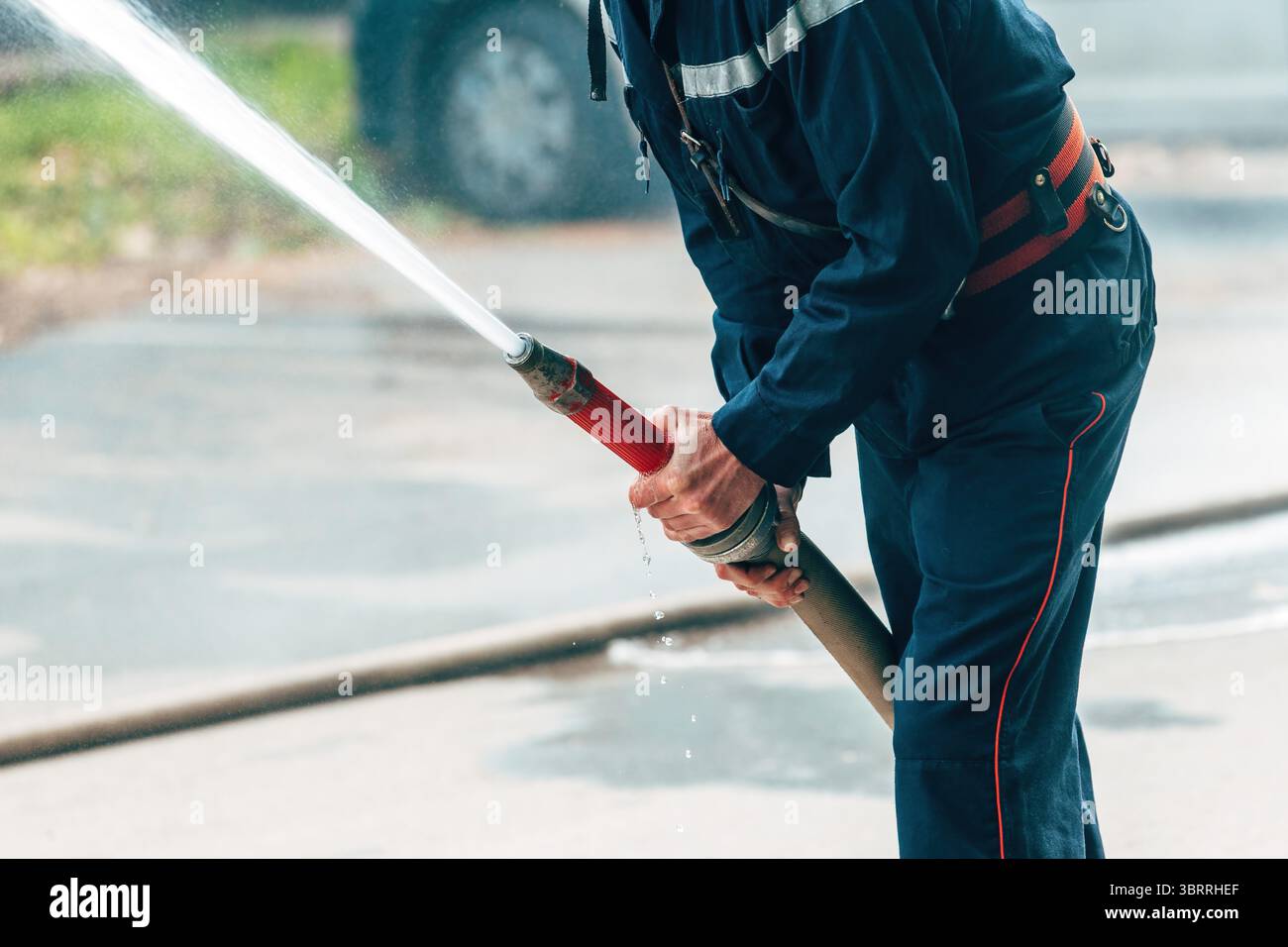 Firefighter spraying water from the hose, selective focus Stock Photo ...