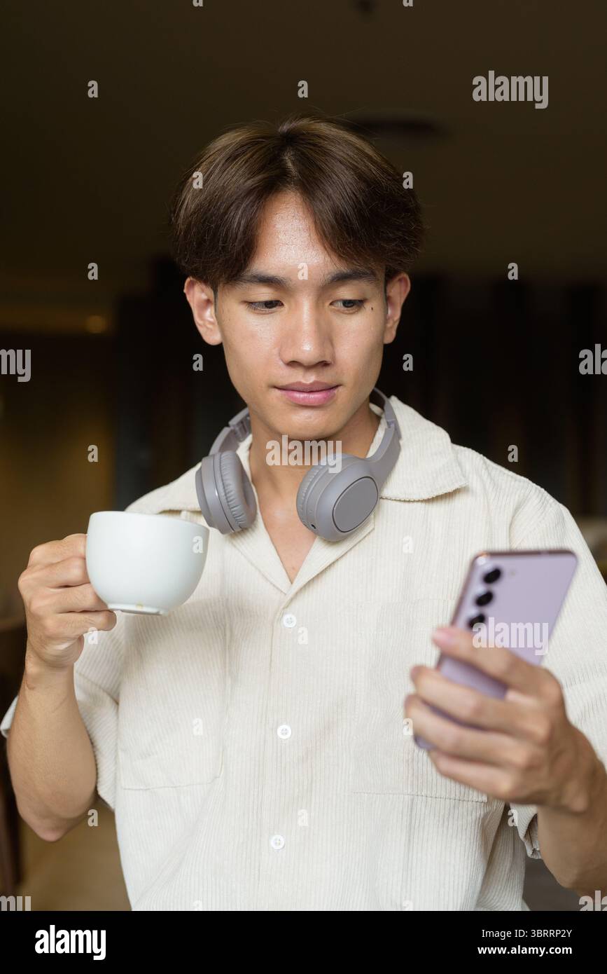 Non binary cute Asian student man sitting in modern coffee shop Stock ...